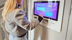 Pessoa a interagir com um quiosque digital, possivelmente para reserva de quarto ou informações.