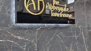 Uma placa com a inscrição 'AT The Abbeygate Townhouse' em uma parede de mármore.