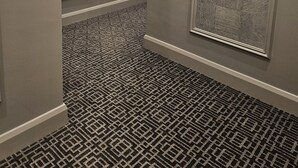 Um corredor com carpete estampado, luminárias fixadas na parede e design texturizado na parede.