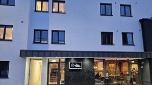 Um edifício moderno com fachada comercial exibindo uma placa com o nome 'The Atelier'.