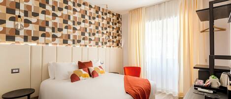 Quarto de hotel moderno com uma cama grande, uma mesa pequena, uma cadeira e uma escrivaninha com cafeteira.