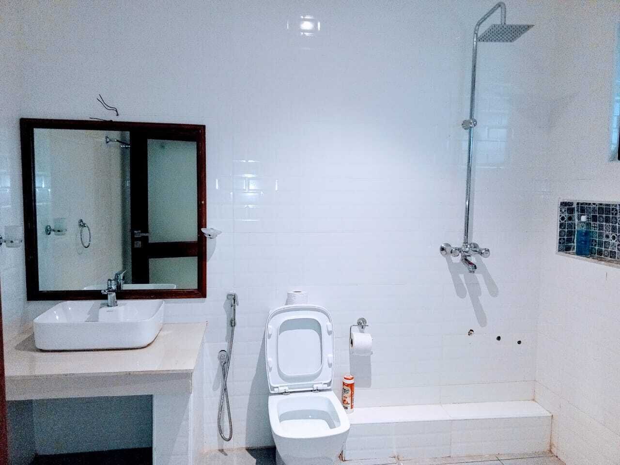 Casa de banho com lavatório, espelho, sanita e chuveiro.