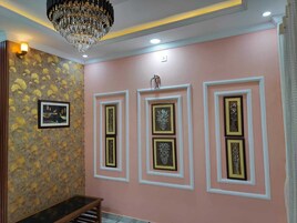 Um corredor com parede rosa, papel de parede estampado à esquerda e um candelabro.