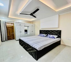 Quarto com cama, guarda-roupa, ventoinha no teto e uma janela grande.