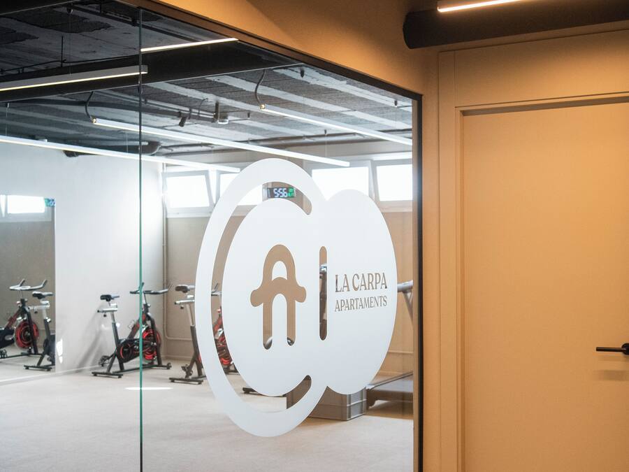 Um interior moderno com parede de vidro exibindo um logotipo e o texto "LA CARPA APARTMENTS".