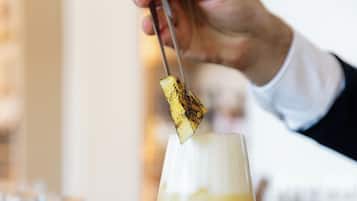 Uma pessoa segurando um copo de coquetel com canudo, com um fundo desfocado de um bar.