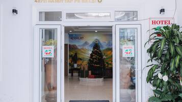 Entrada de hotel com árvore de Natal e um mural com paisagem de montanhas.