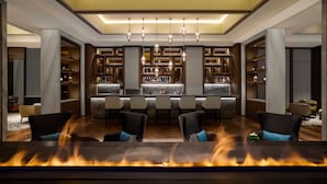 Uma área de bar moderna com balcão central, assentos e lareira.