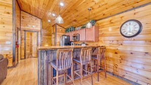 Interior de uma cabana rústica, com cozinha que inclui balcão e espaço para sentar.