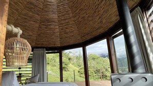 Quarto com uma cama grande, teto de madeira e vista para o exterior.