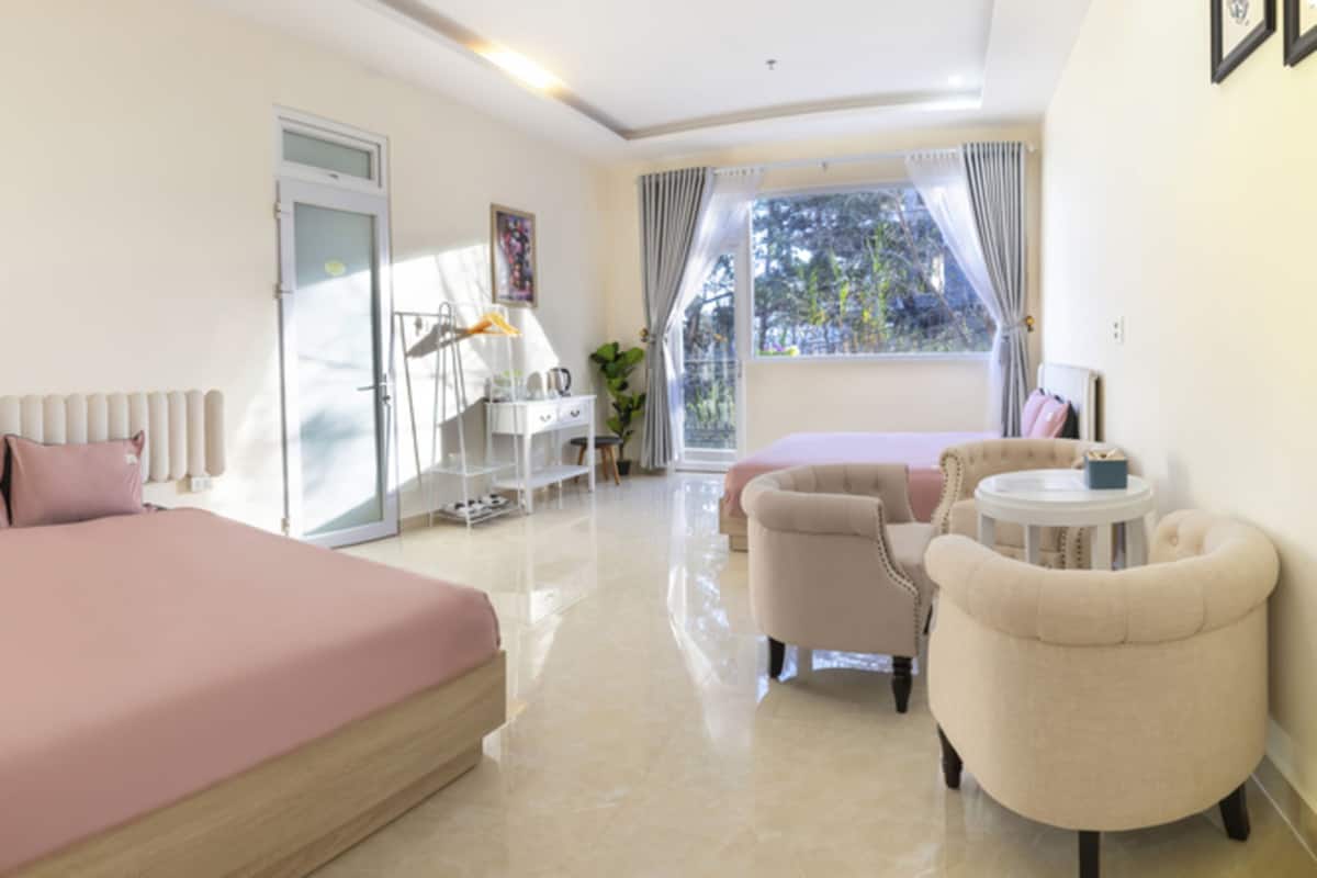 Quarto de hotel com duas camas, uma escrivaninha, uma cadeira e uma janela com cortinas.
