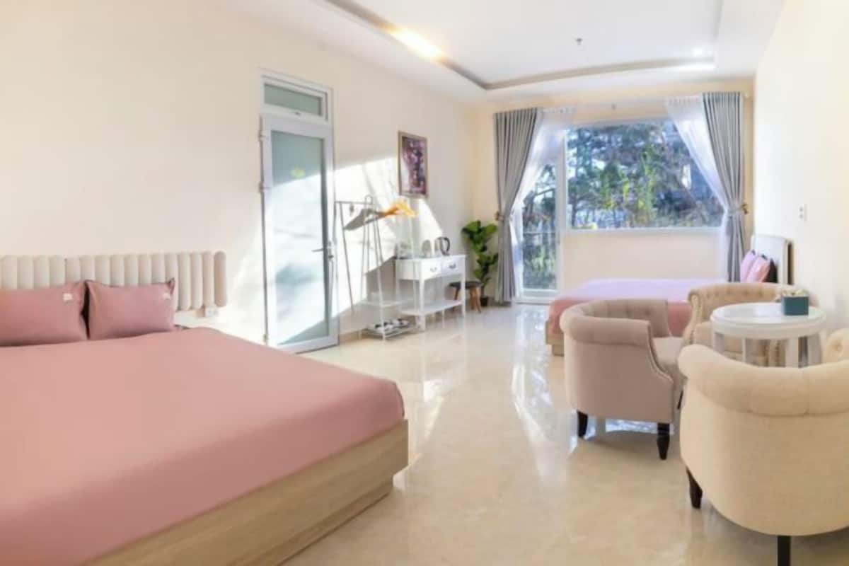 Quarto de hotel com cama, escrivaninha, cadeira e janela com cortinas.