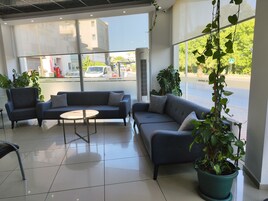 Um lobby de hotel moderno com um sofá cinzento, uma pequena mesa redonda e plantas em vasos.