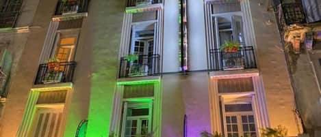 Um edifício com várias andares, varandas, janelas amplas e uma entrada central.
