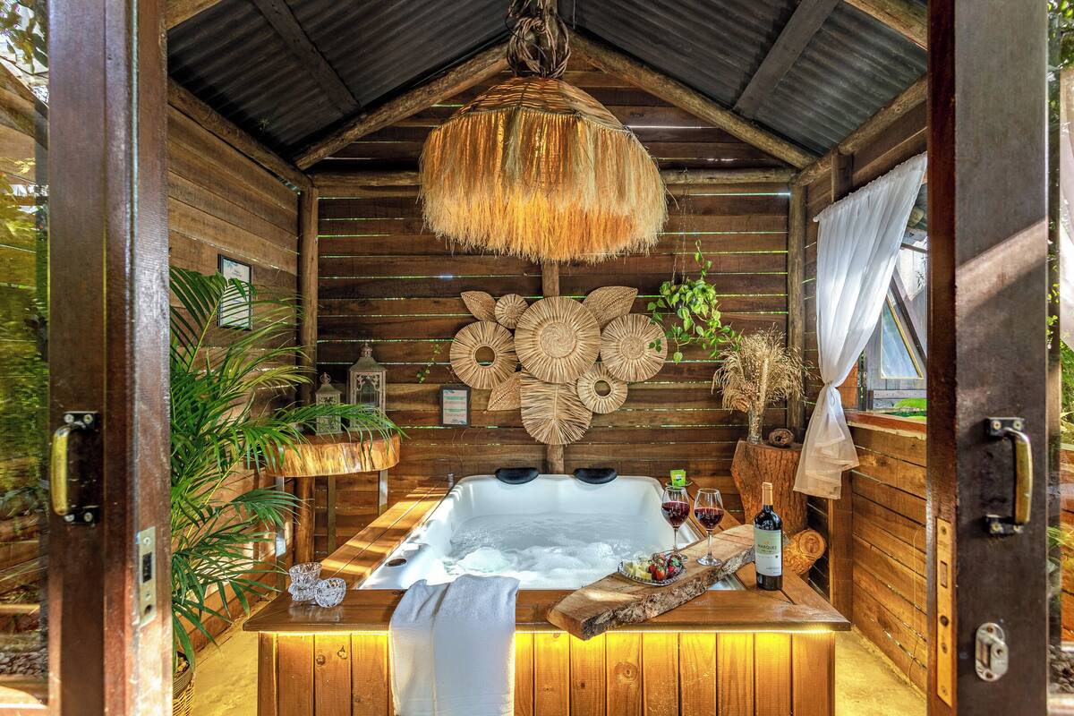 Uma cabana de madeira com uma banheira de hidromassagem, um cesto pendurado e decoração de parede em madeira.
