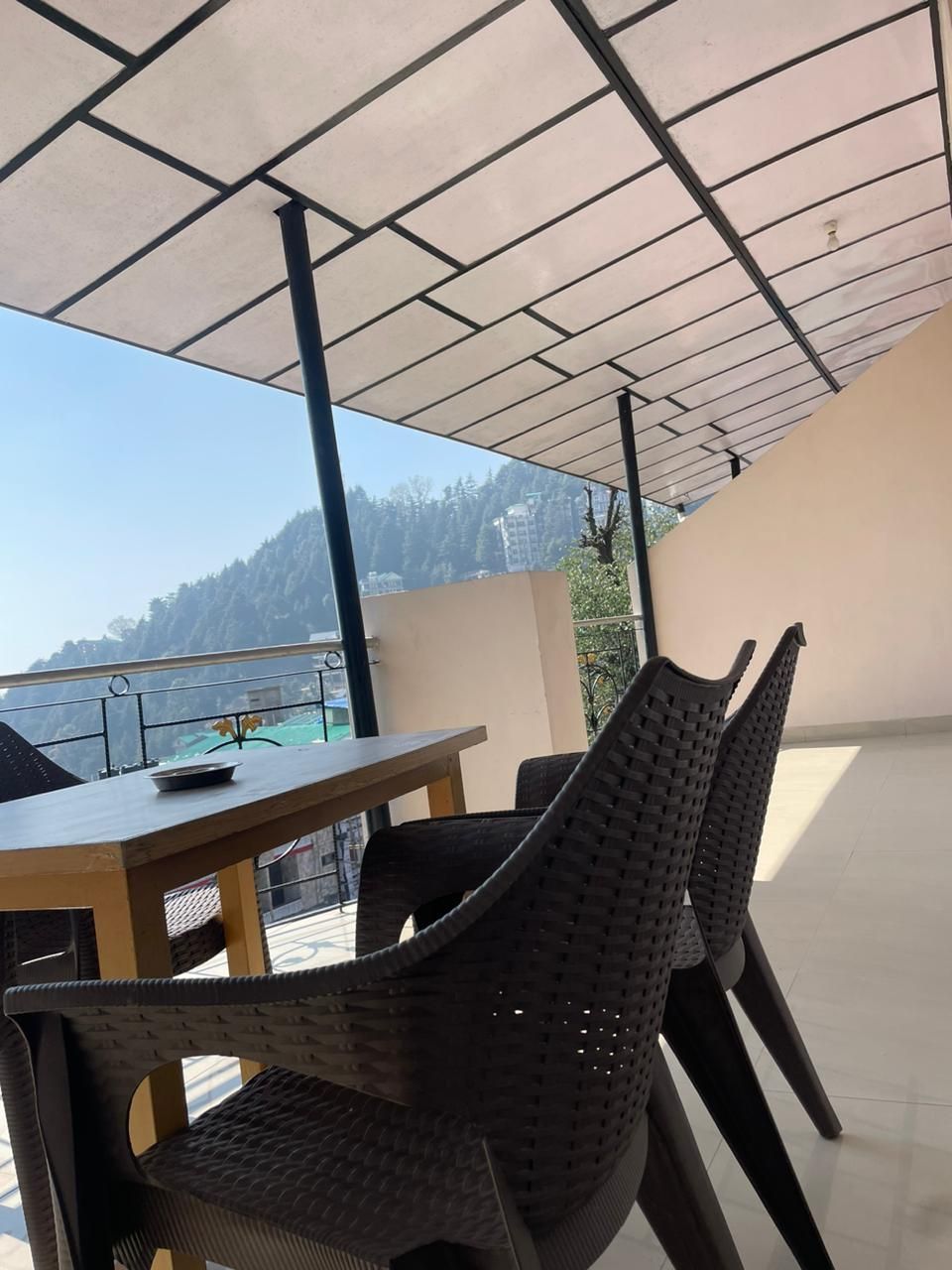 Varanda com mesa e cadeiras, vista para uma paisagem montanhosa.