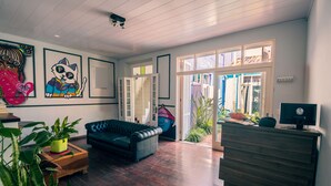 Uma sala de estar moderna com um sofá azul escuro, uma mesa de centro de madeira e uma janela grande com vista para edifícios.