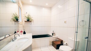 Uma casa de banho moderna com uma grande pia, banheira, sanita e cabine de duche em vidro.