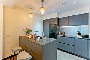 Cozinha moderna com ilha central, banquetas e iluminação pendente.