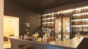 Uma área de bar moderna com um balcão comprido, banquetas e uma variedade de garrafas e copos.