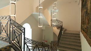 Escadaria com grades geométricas e iluminação pendente.