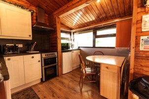 Uma cozinha compacta com armários de madeira, fogão e um espaço de refeições com mesa e cadeiras.