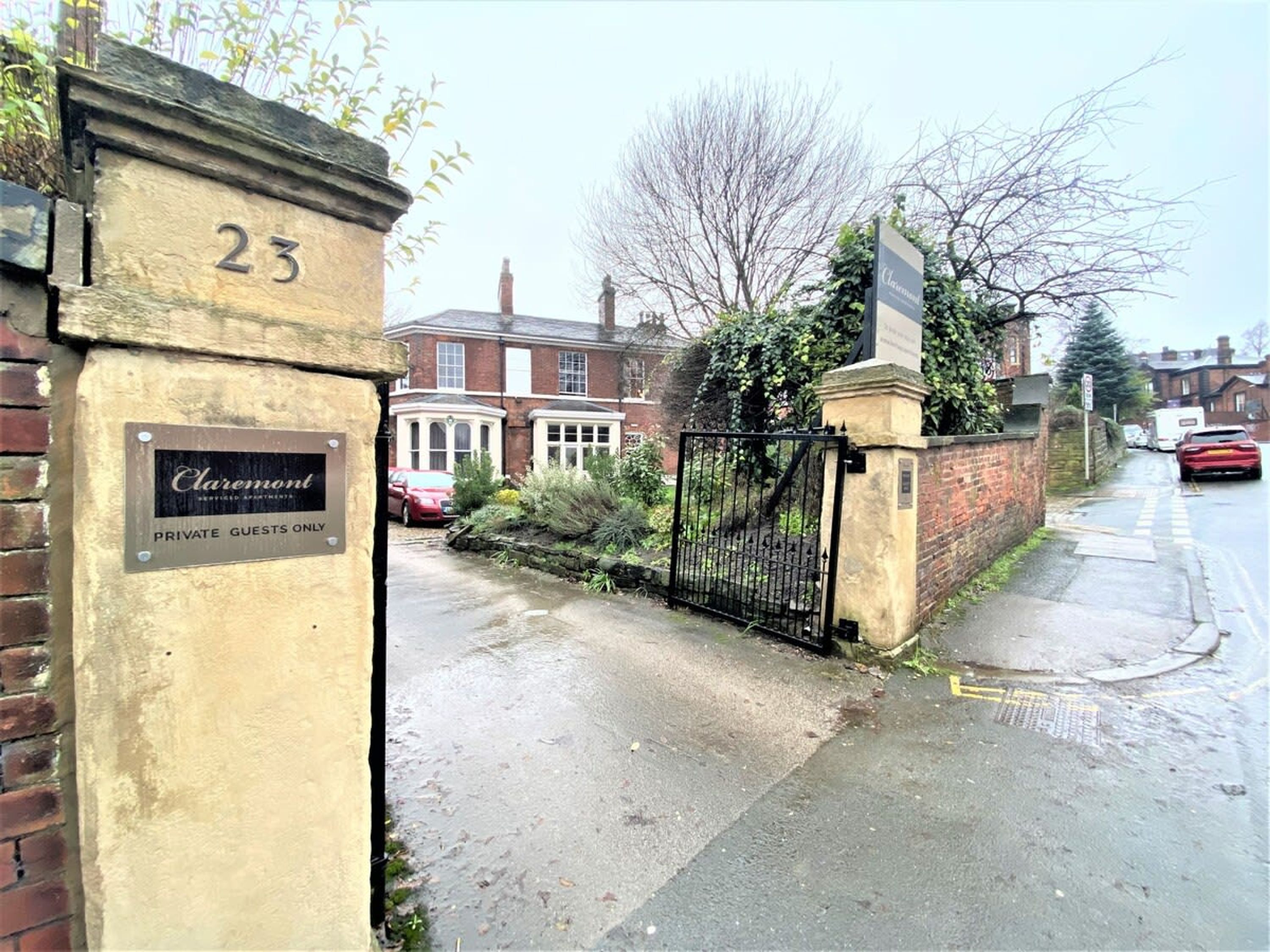 Uma entrada com portão para uma propriedade com a placa 'Claremont', indicando 'Apenas Hóspedes'.
