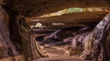 Uma caverna com estalactites e estalagmites, um estreito corredor e um elemento aquático.