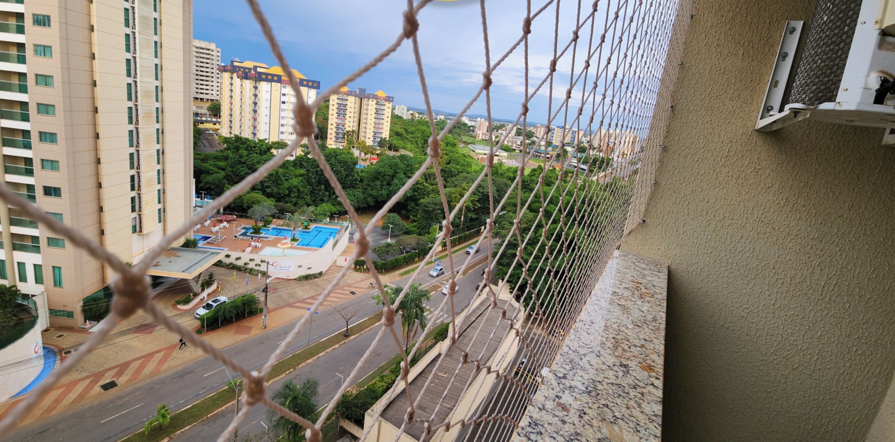 Um edifício alto com vista para uma piscina e vegetação ao redor.