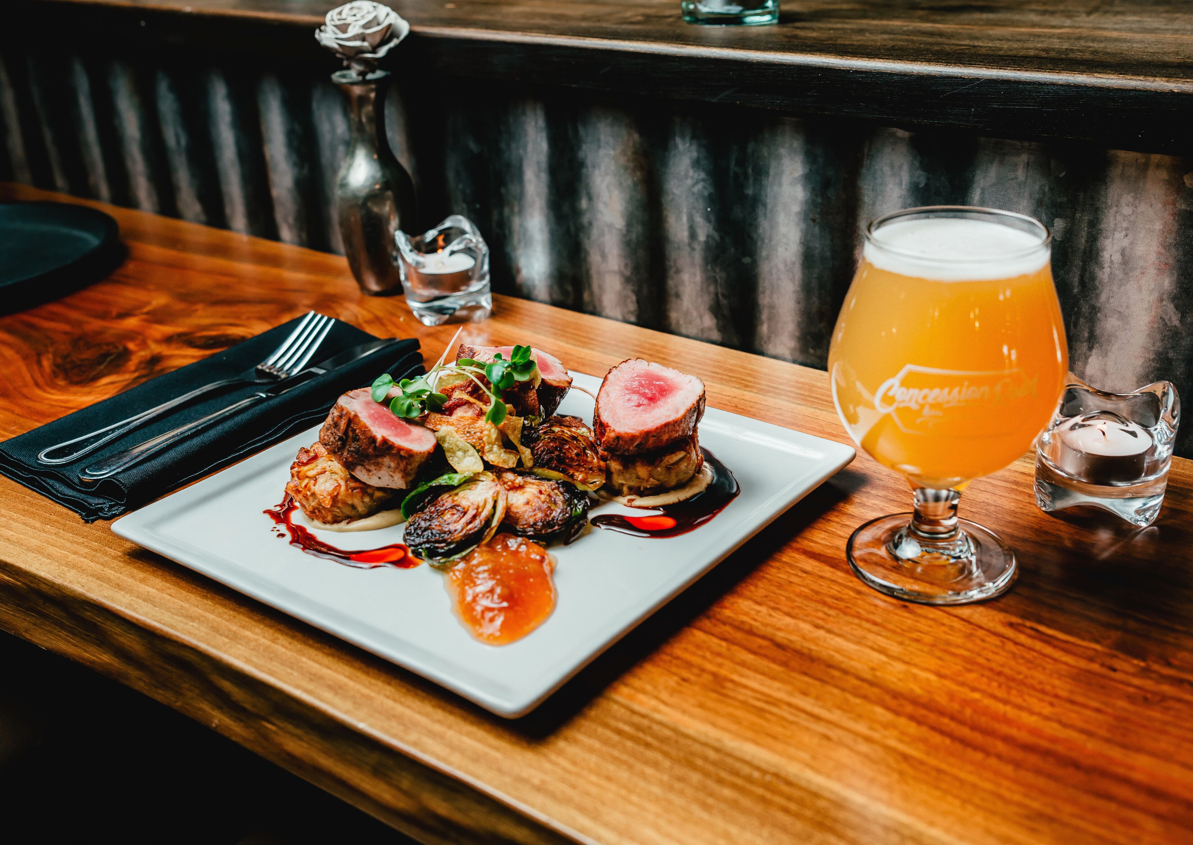 Prato de comida com um copo de cerveja sobre uma mesa de madeira.