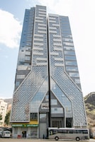 Um edifício alto com fachada geométrica marcante e uma loja à venda com a inscrição