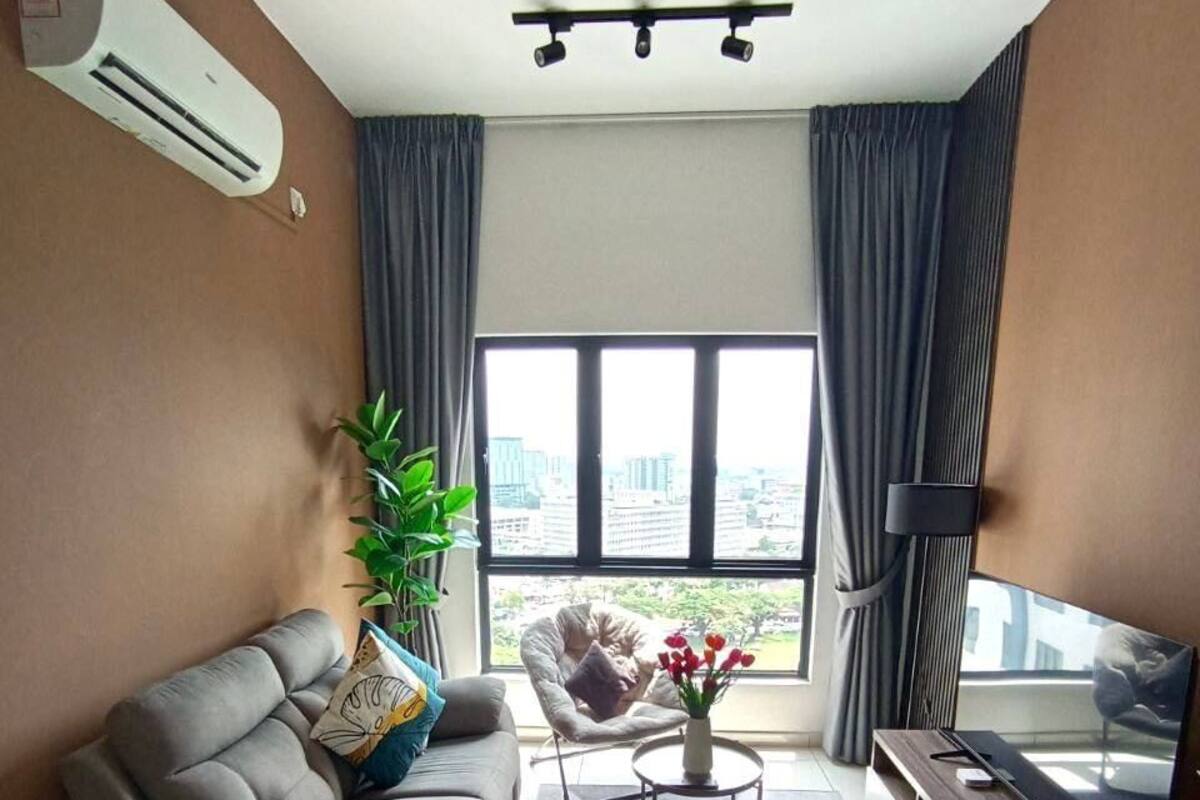Uma sala de estar moderna com um sofá cinza, uma mesinha de centro, uma TV sobre um suporte de madeira, um ventilador de teto e uma grande janela com cortinas.