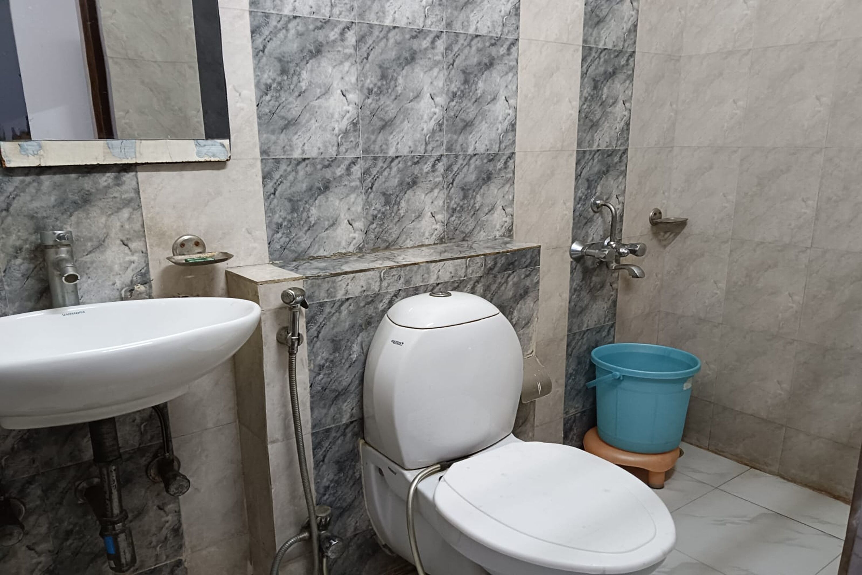 Casa de banho com lavatório, sanita e chuveiro brancos.