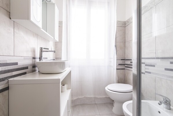 Casa de banho moderna com lavatório branco, sanita e zona de duche.