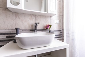Uma casa de banho moderna com uma pia branca, um espelho em cima e um painel de azulejos.