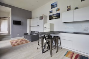 Uma cozinha moderna com mesa de jantar, banquetas e geladeira.