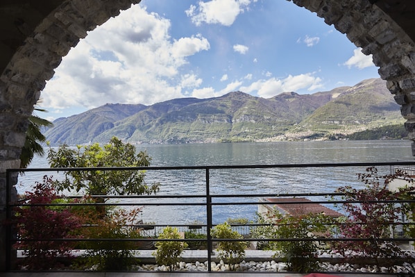 Vista através de um arco de pedra, com um lago e montanhas ao fundo.