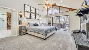 Um quarto espaçoso com uma cama grande, ventilador de teto e vista para o exterior.