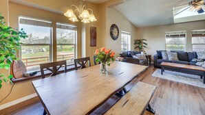 Uma sala de estar ampla com uma grande mesa de jantar de madeira, um sofá e um ventilador de teto.