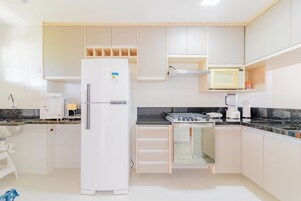Cozinha compacta com geladeira, fogão, micro-ondas e armários.