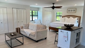Quarto com cama, mesa de cabeceira e ventoinha no teto.