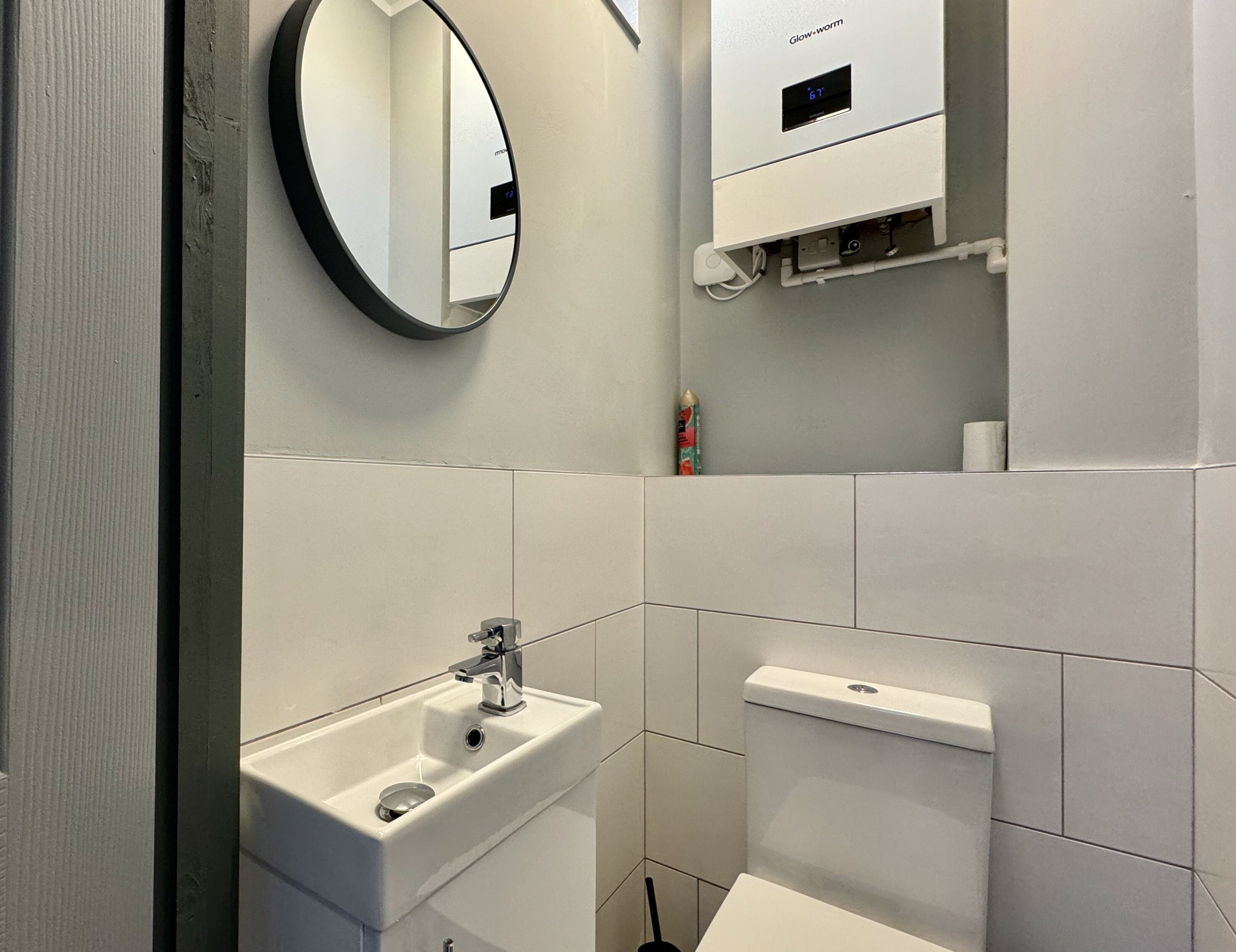 Uma casa de banho moderna com lavatório branco, espelho, sanita e aquecedor fixado na parede.