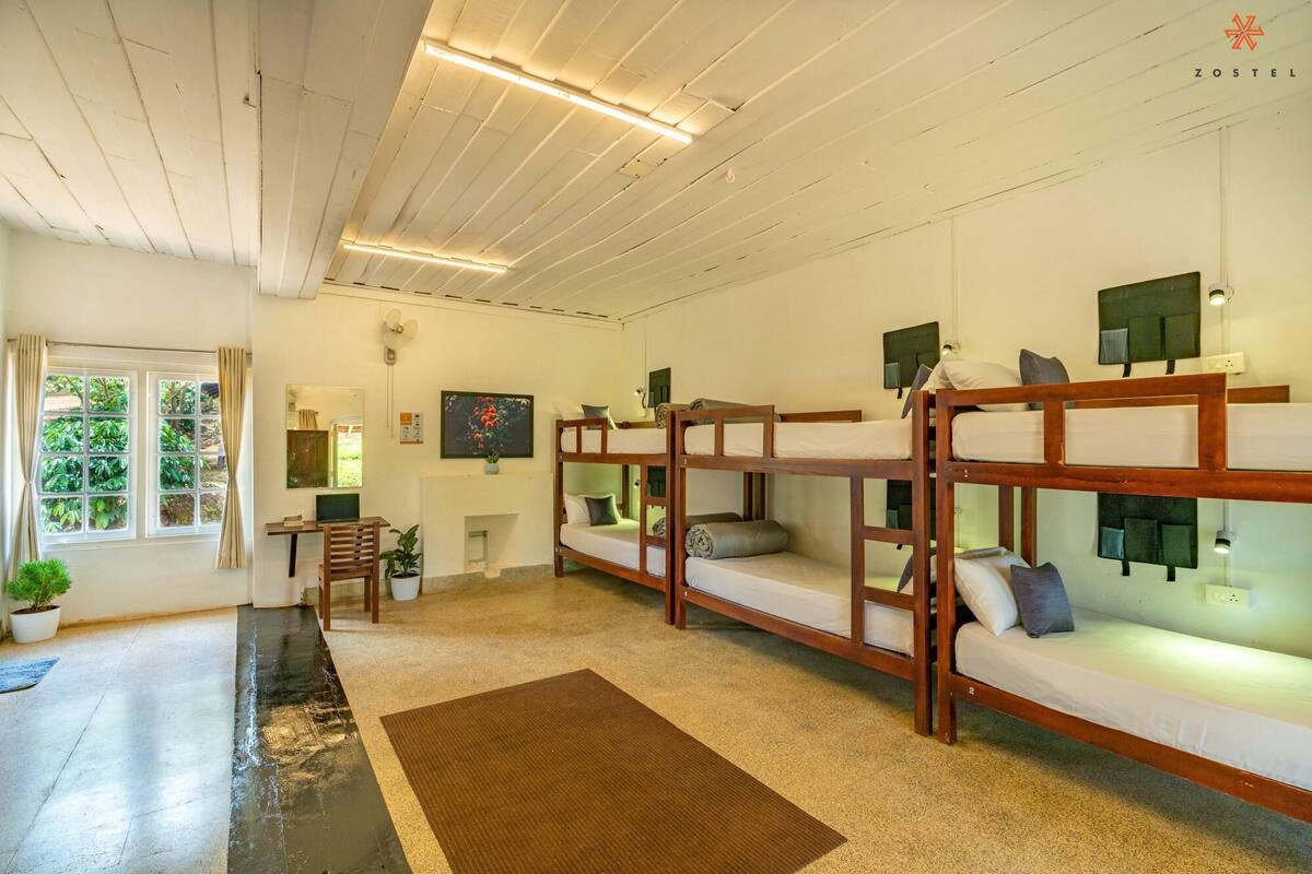 Um quarto com beliches, lareira, escrivaninha e janela com cortinas.