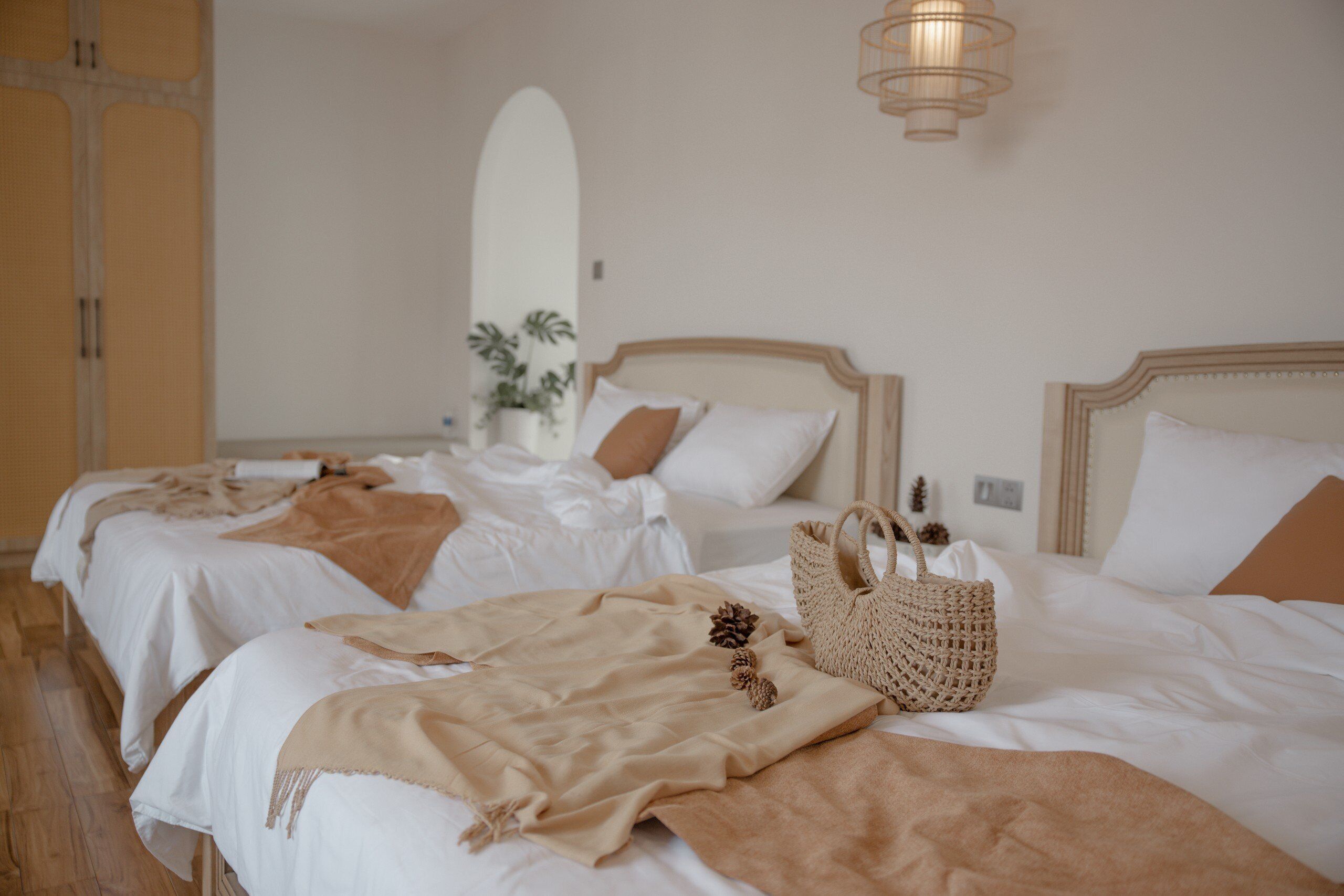 Quarto de hotel com duas camas, um espelho grande e um candeeiro suspenso.