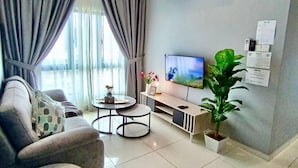Uma sala de estar moderna com ventilador de teto, televisão de tela plana, sofá, mesa de centro e planta em vaso.