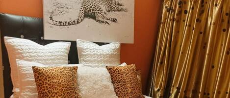 Quarto com cama, almofadas, cobertor e almofada estampada com onças.