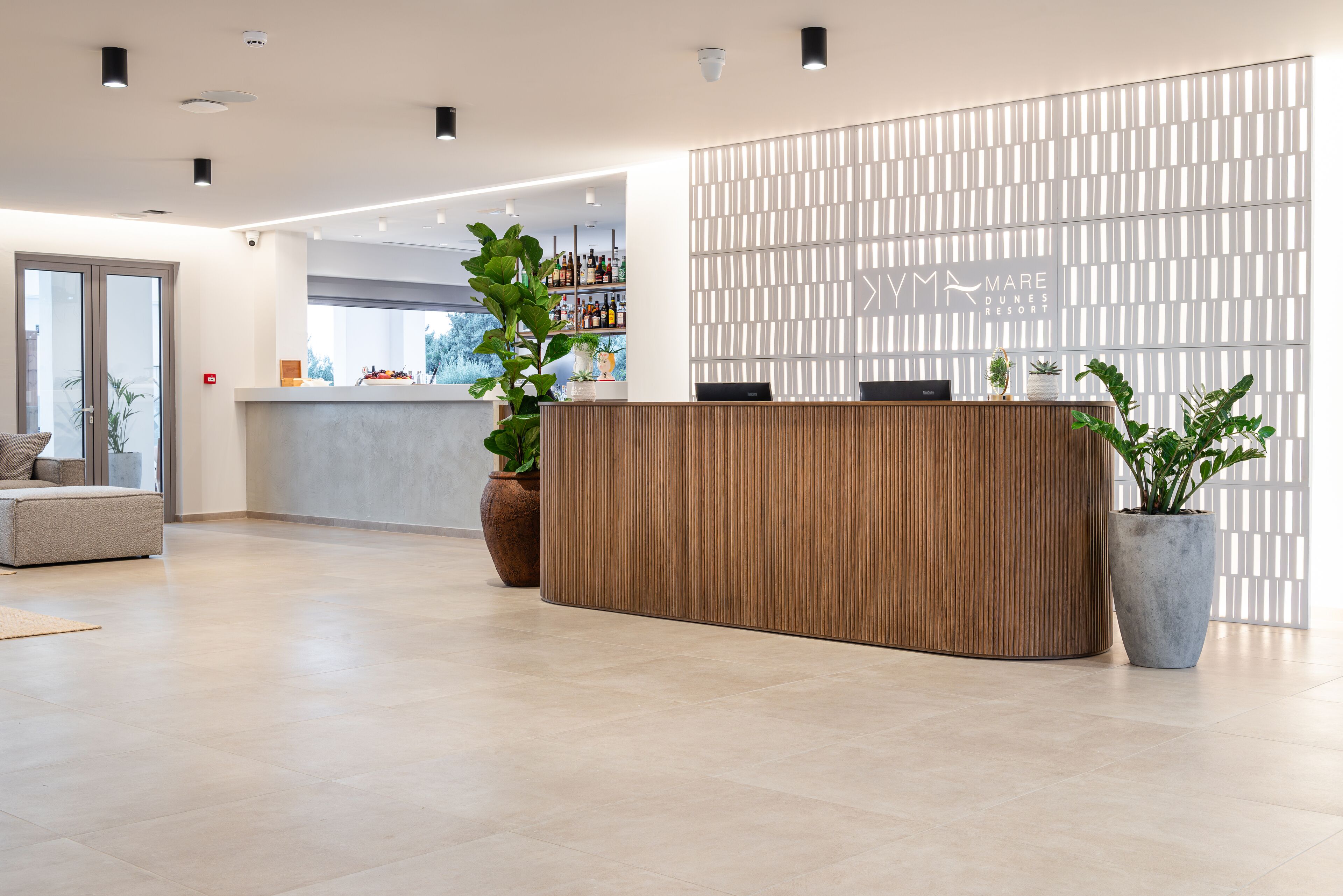Uma área de recepção moderna com balcão de madeira, plantas em vasos e vista para o espaço exterior.