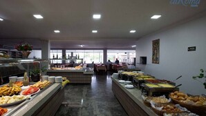 Uma área de buffet com diversos alimentos e uma área de estar ao fundo.