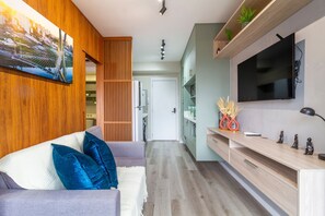 Uma sala de estar moderna com sofá, televisão e painéis de madeira.