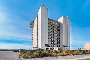Hotel de vários andares com design moderno, apresentando varandas em cada pavimento e uma torre central imponente.